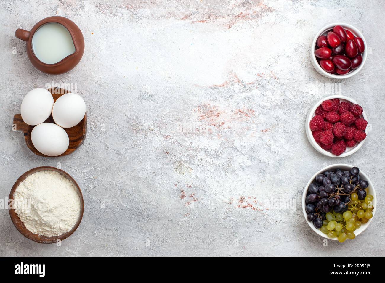 top view whole raw eggs with flour fruits and milk on white background ...