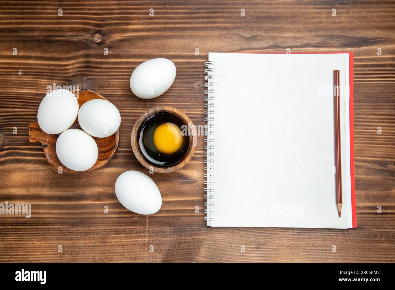 top view whole raw eggs with notepad on brown wooden background meal ...