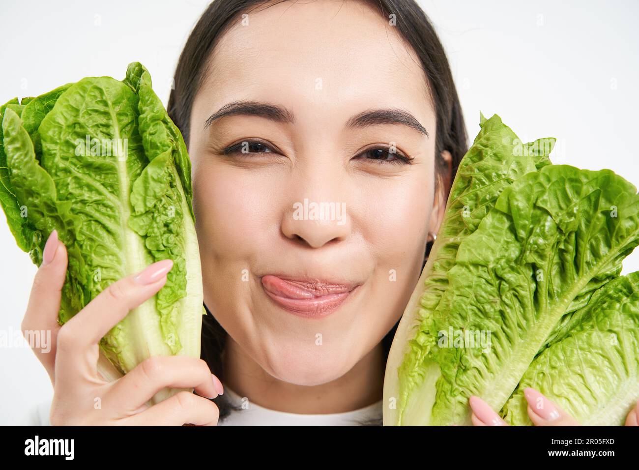 Portrait of cute young woman shows her face with cabbage, likes ...