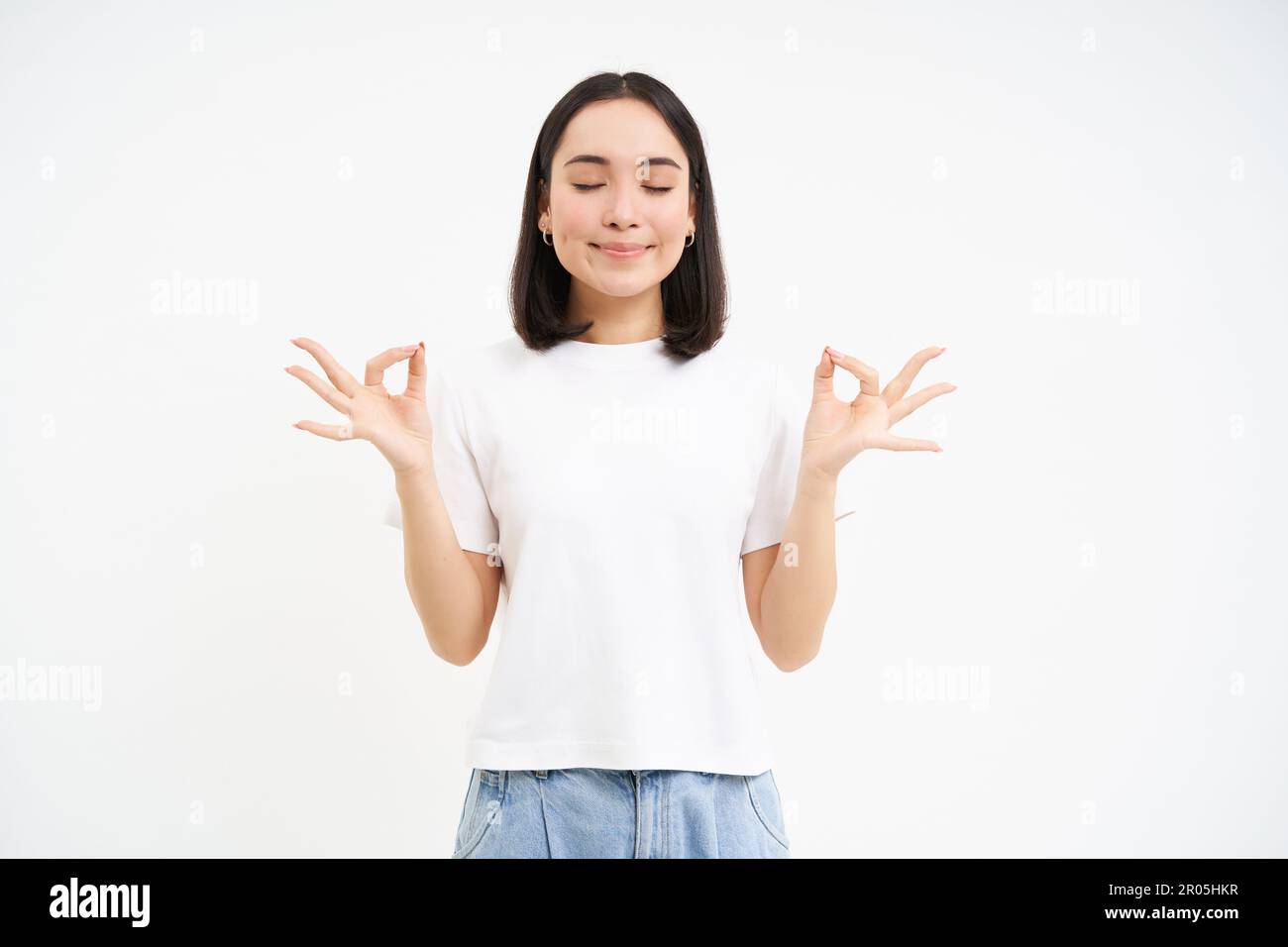 Peaceful smiling asian woman, standing calm and relaxed, holds hands in ...