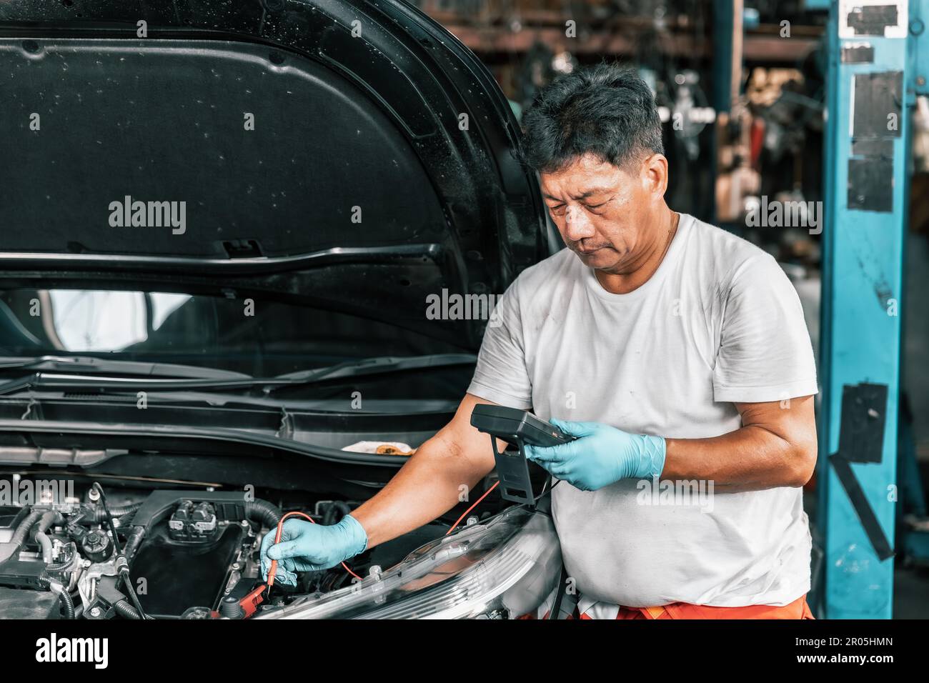 Experienced auto mechanics inspect car battery terminals and voltage to ...