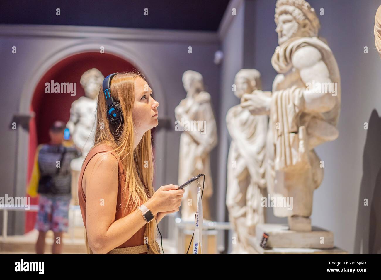 Portrait of contemporary young woman looking at sculptures and ...