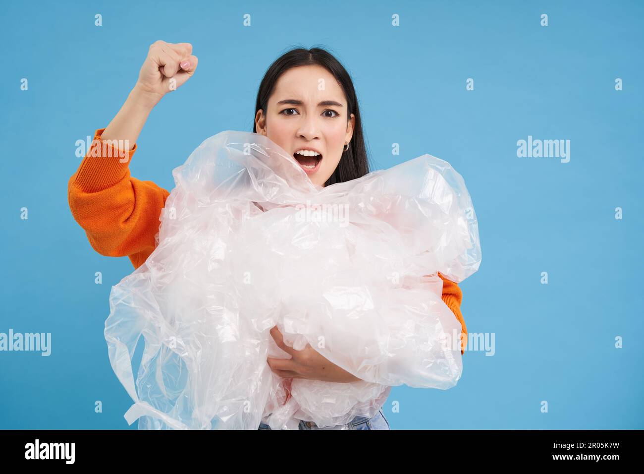 Angry eco-activist holding plastic waste, raising fist and fighting for ...