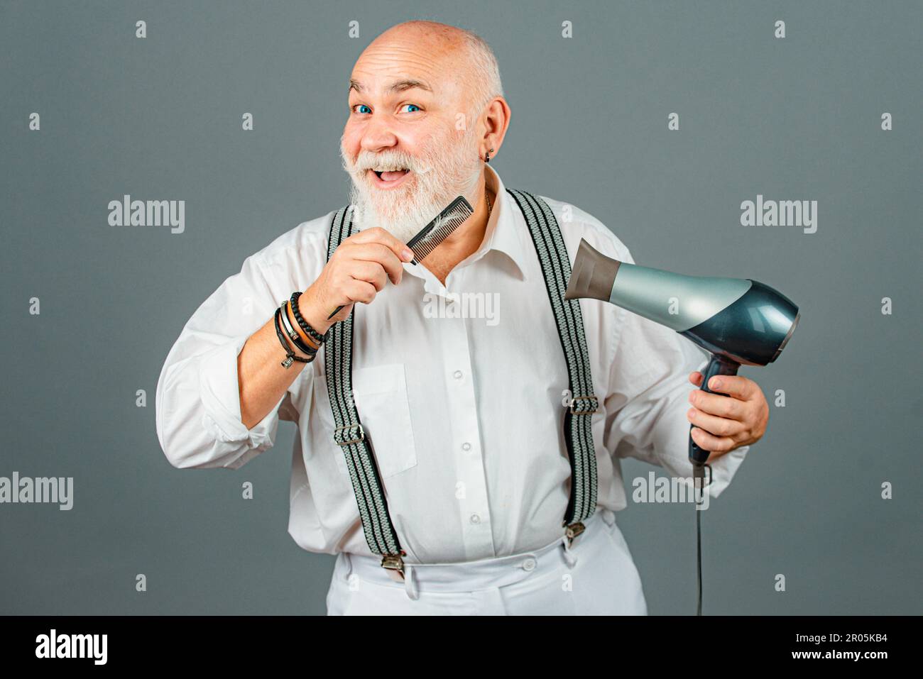 Hairdresser barber with hair dryer and comb drying beard and moustache ...