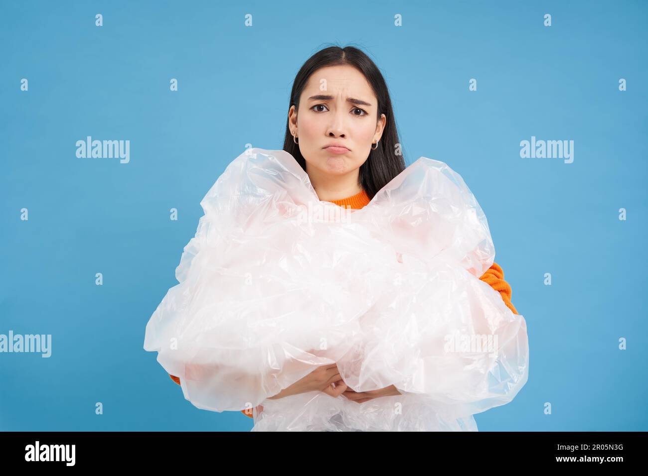 Sad woman eco-activist, holding plastic waste and looking upset. Young ...
