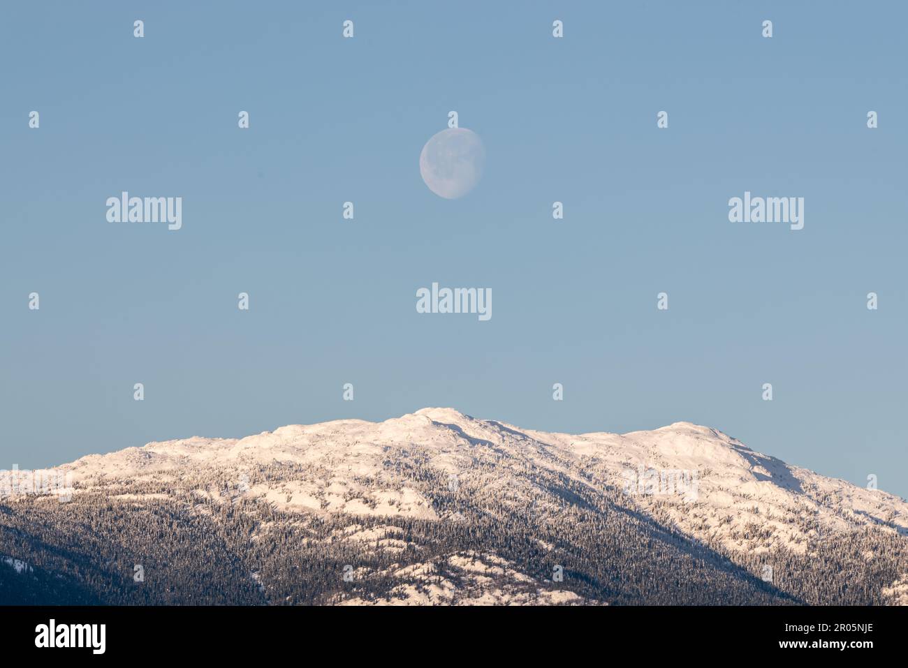 Moon setting over beautiful snow capped mountains in northern Canada ...