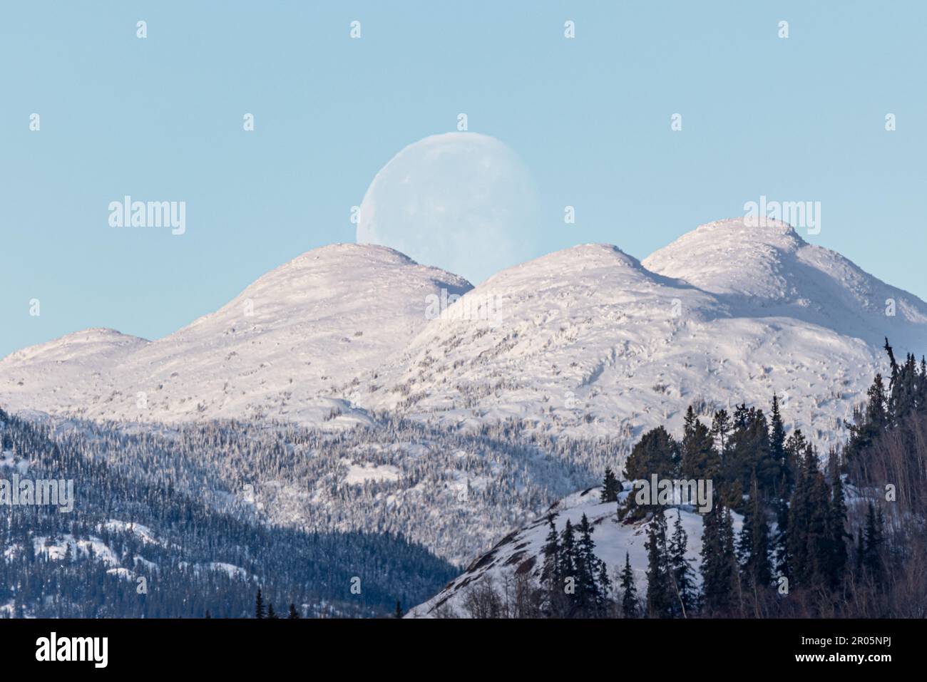 Moon setting over beautiful snow capped mountains in northern Canada ...