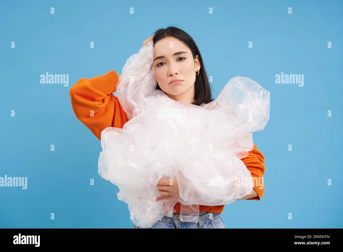 Young asian woman with plastic waste, looking bothered by recycling ...