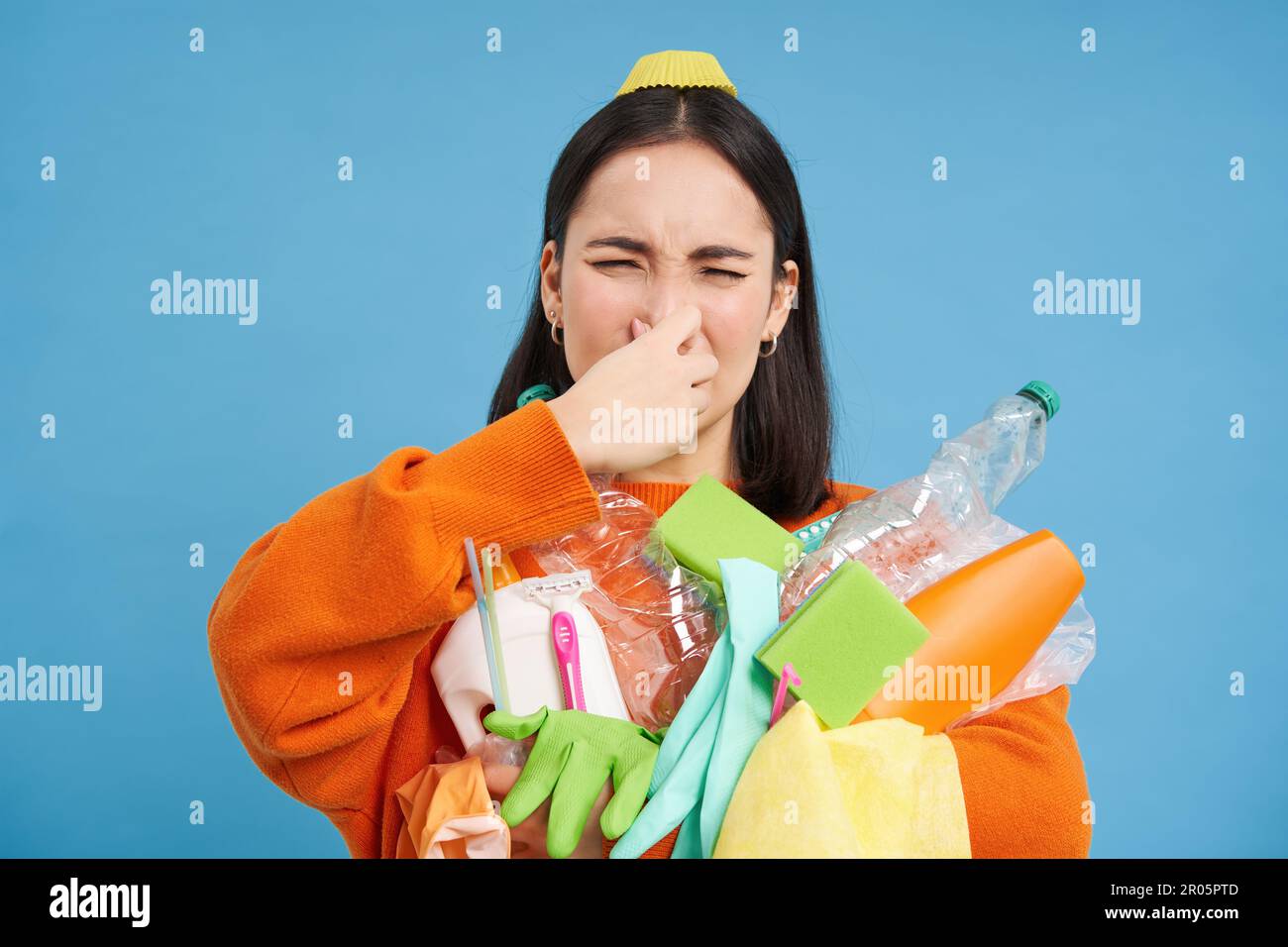 Portrait of woman shuts her nose from digust, holding stinky garbage ...