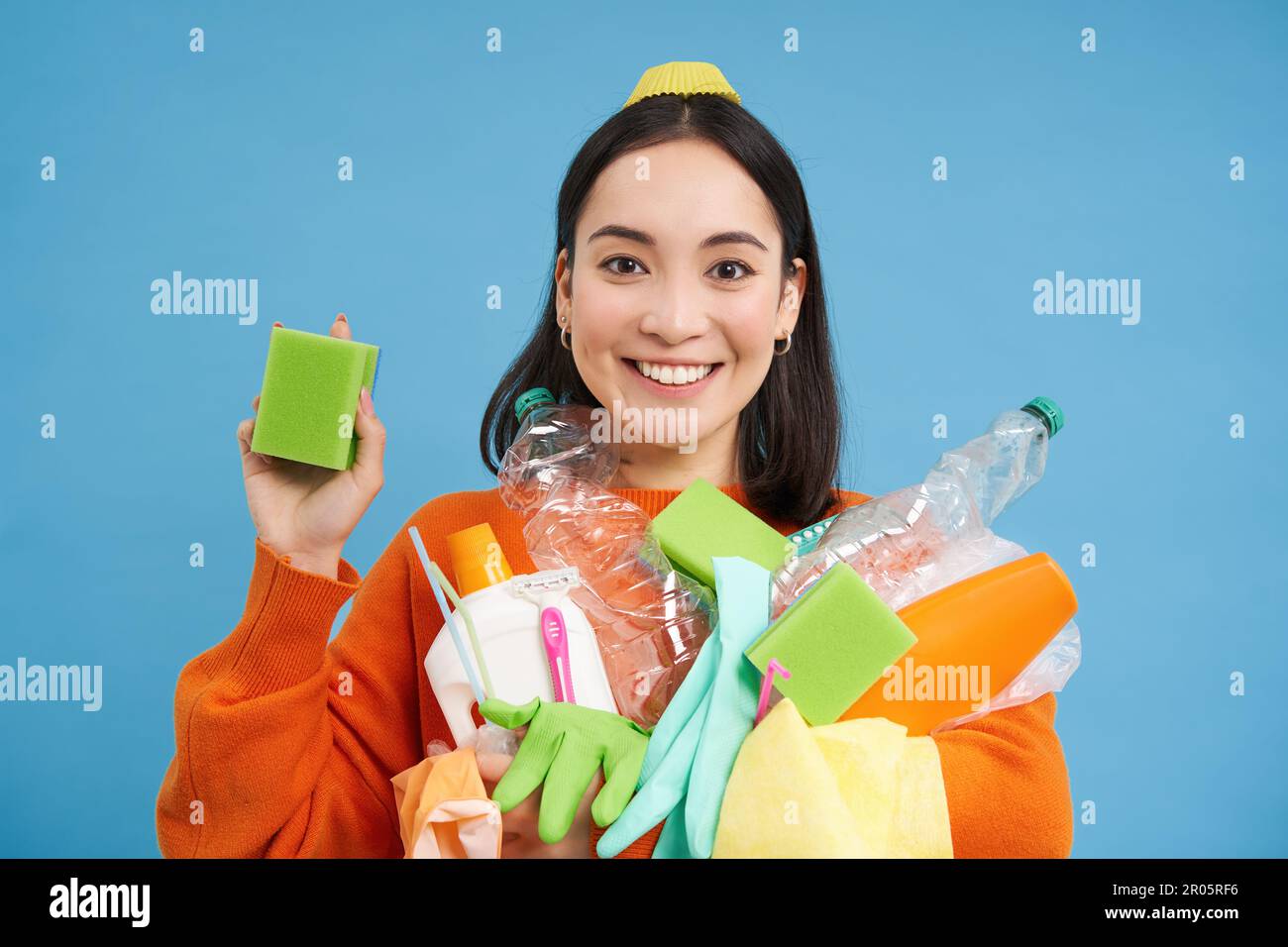 Enthusiastic asian girl showing cleaning sponge, holding empty plastic ...