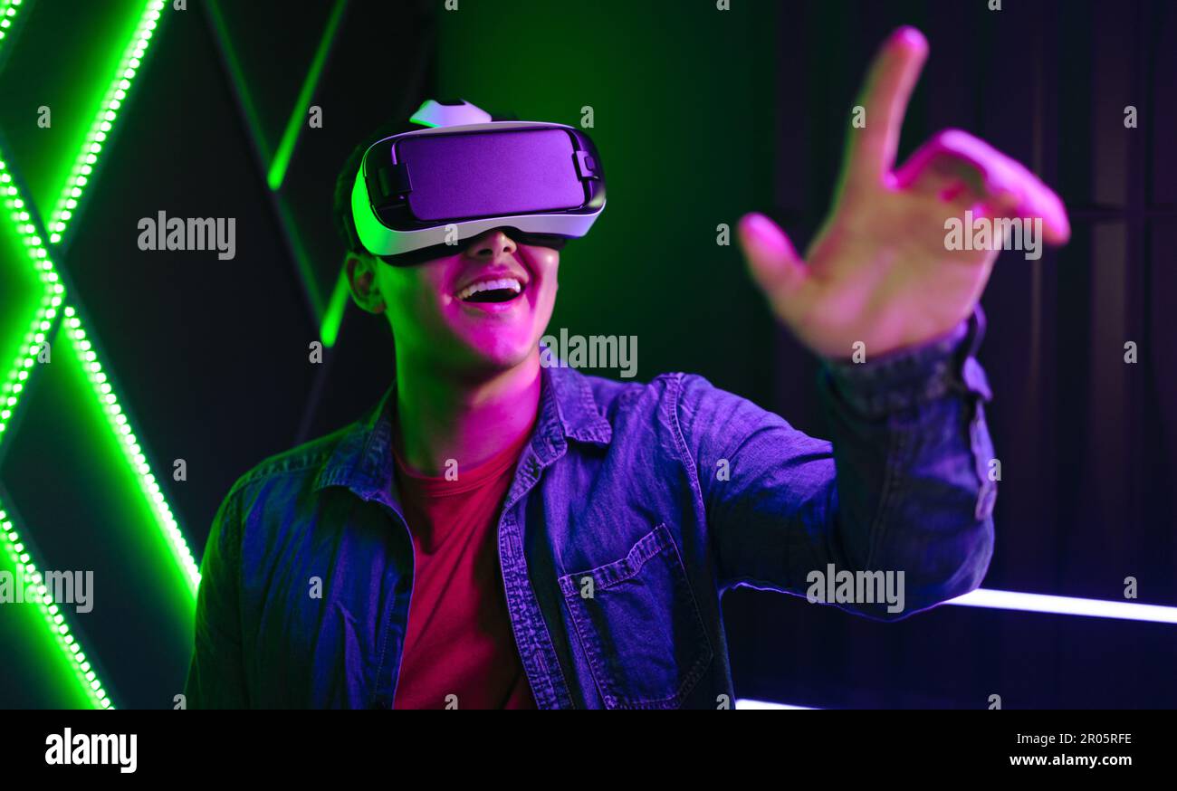 Young man dons his VR goggles and steps into a virtual reality game ...
