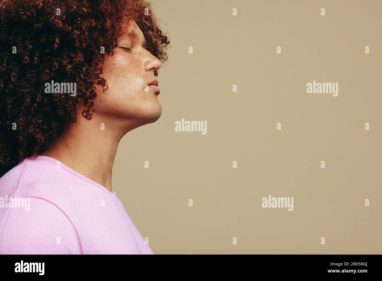 Young man standing in a studio with his eyes closed, embracing his ...