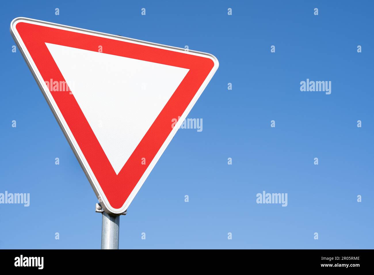 Give way triangle road sign with blue sky Stock Photo - Alamy