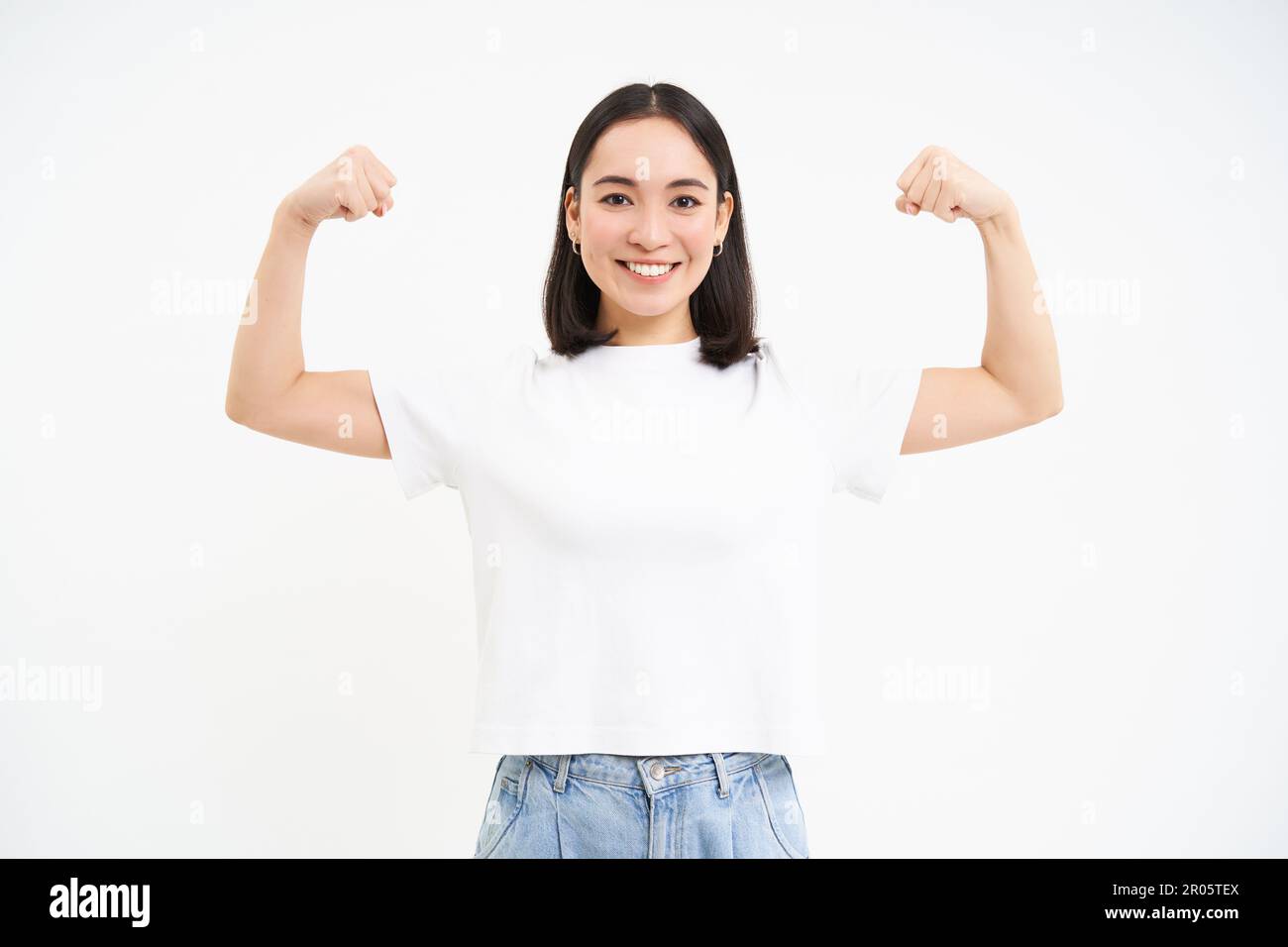 Portrait of young asian woman, flexing muscles, showing biceps and ...