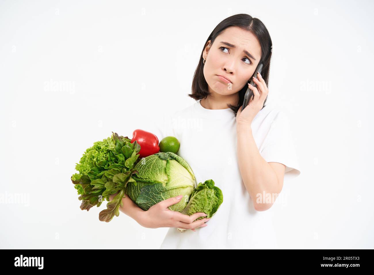 Image of girl with vegetables, making phone call with sad, unhappy face ...
