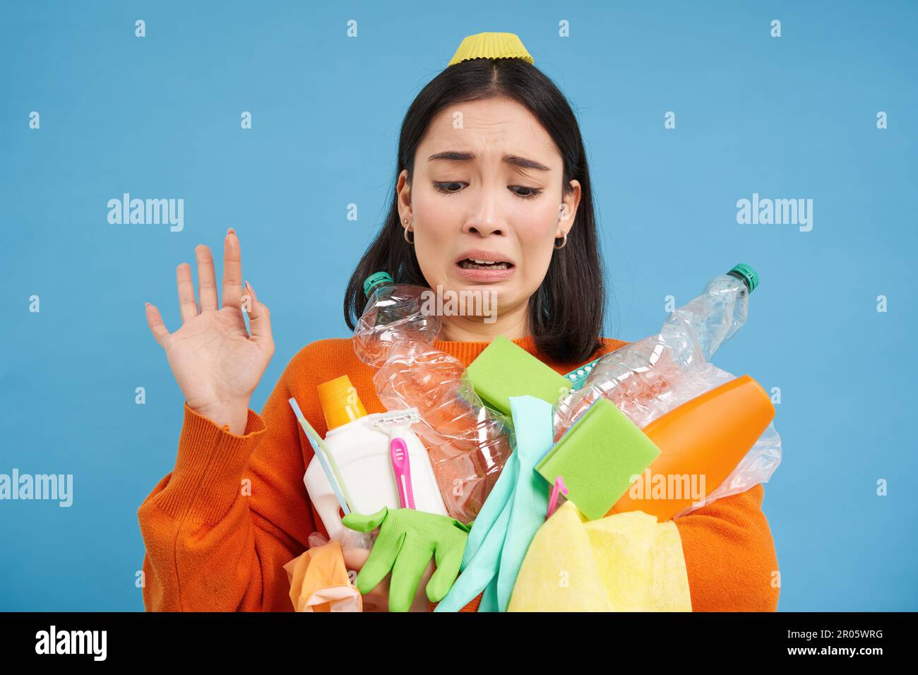 Disgusted asian woman, holding empty bottles, garbage for recycling ...
