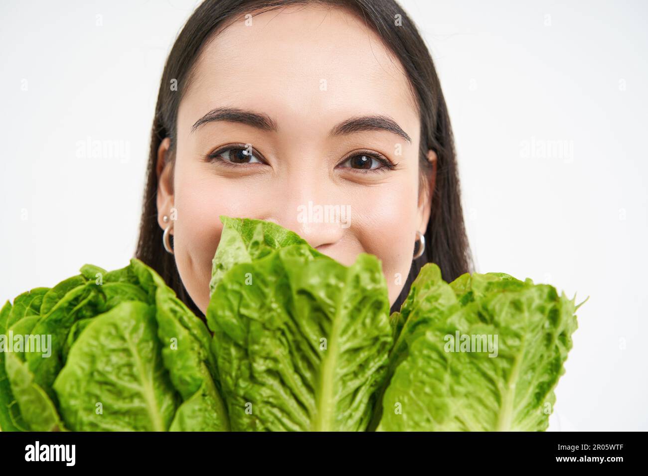 Close up portrait of happy korean woman, shows her face with lettuce ...