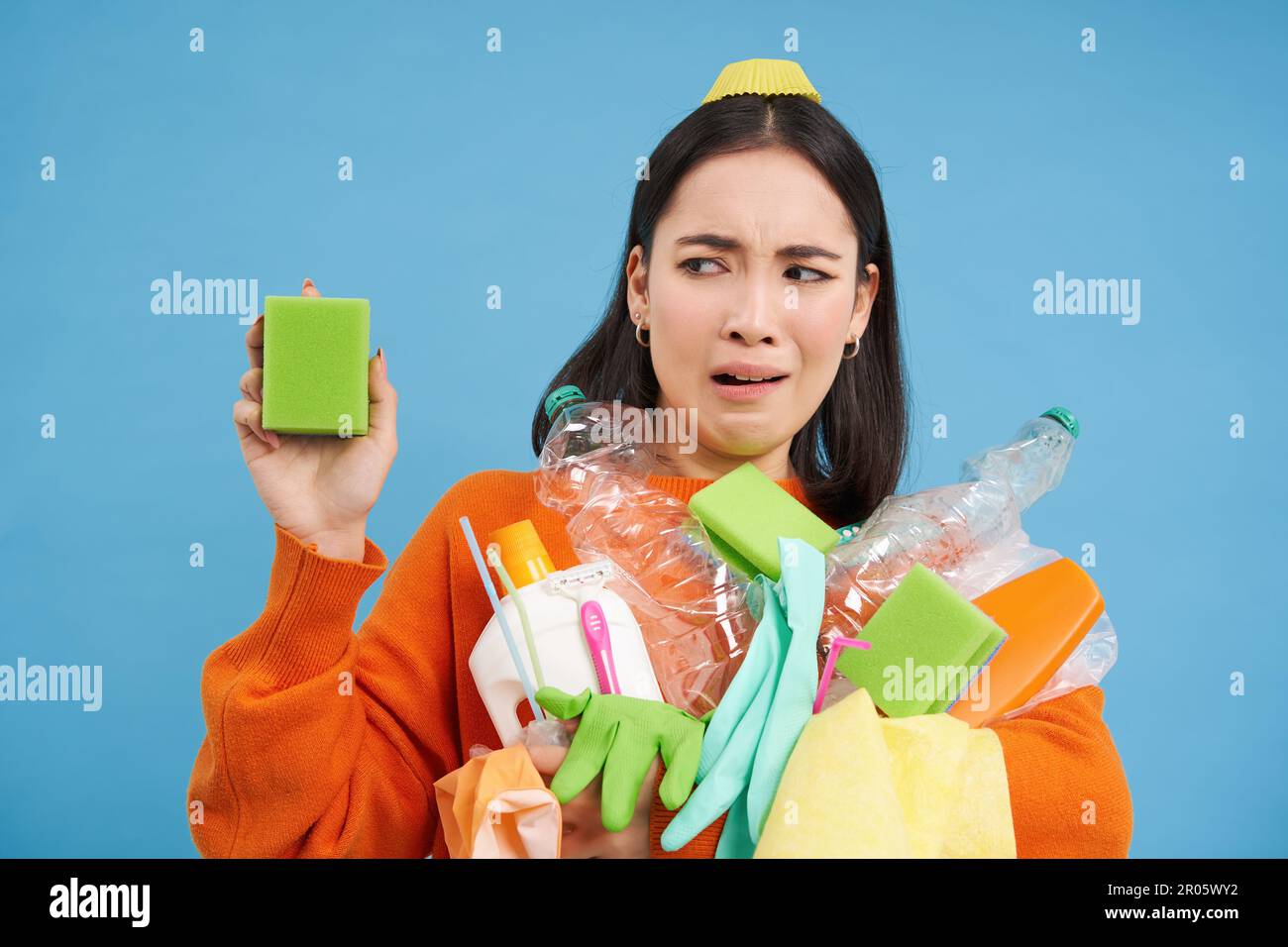 Portrait of asian woman looking disgusted at dirty sponge, holding ...