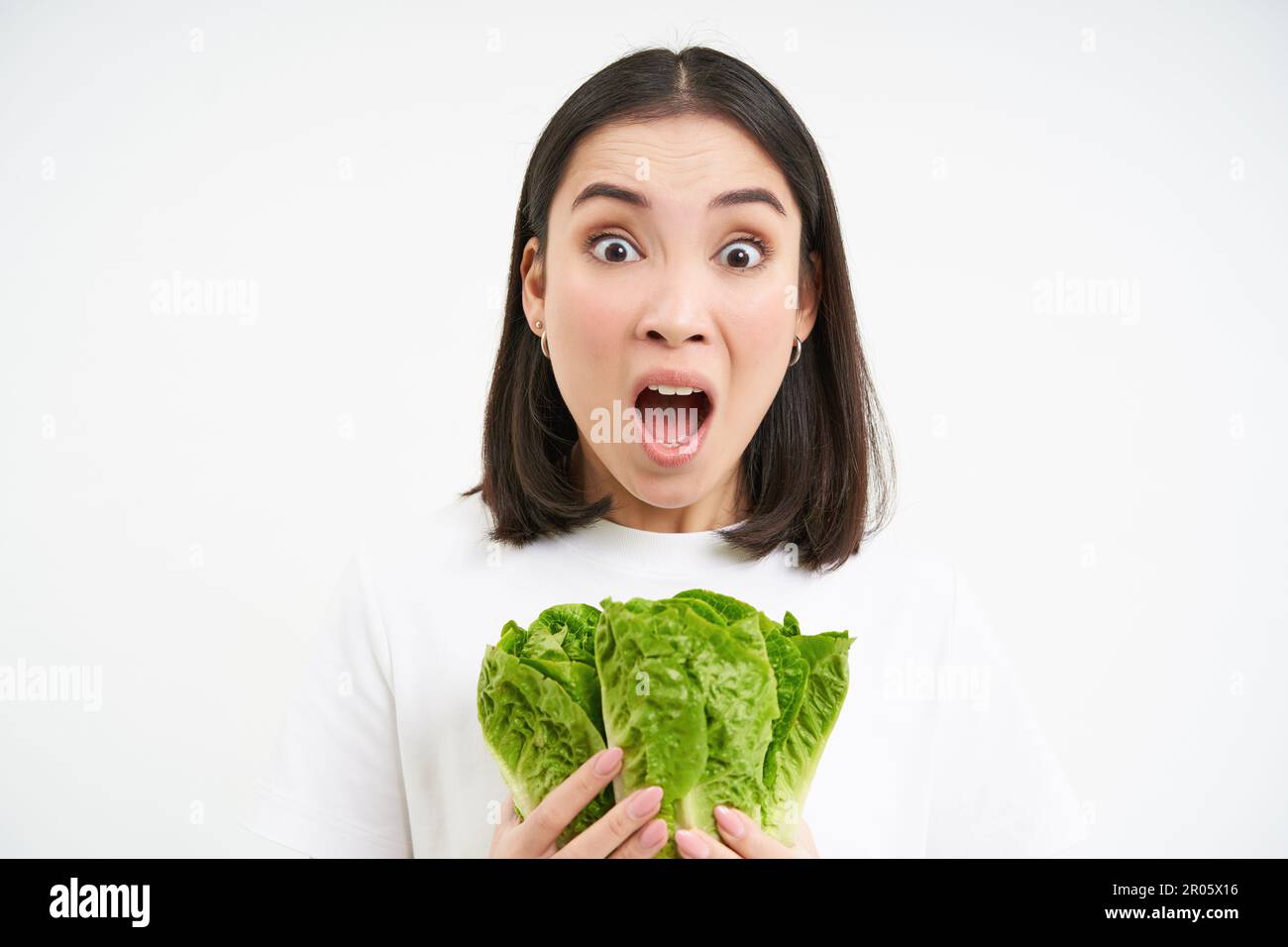 Woman with shocked face, screams, holds vegetable, raw food, eats ...