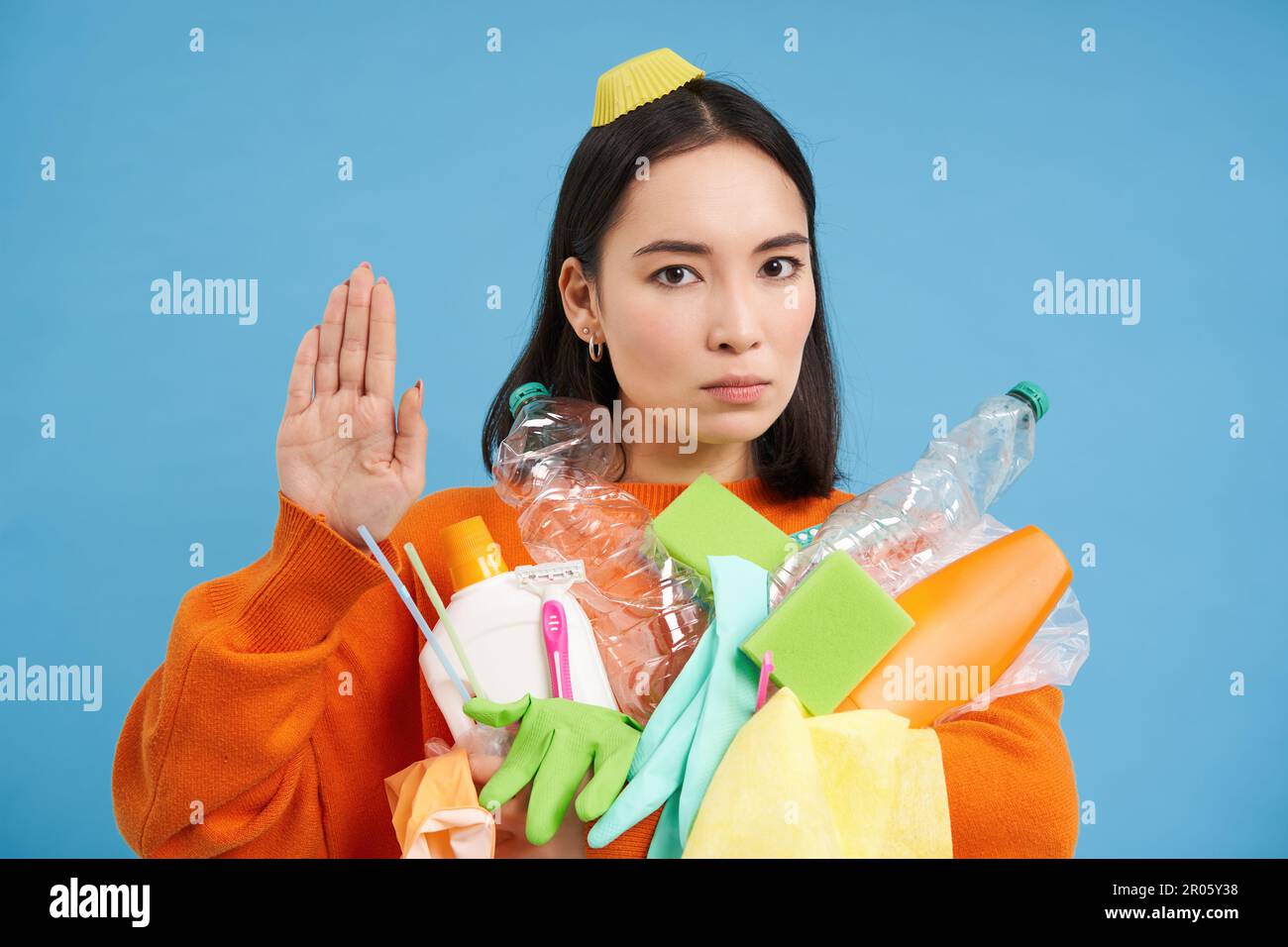 Portrait of serious asian woman shows stop sign, holds plastic for ...