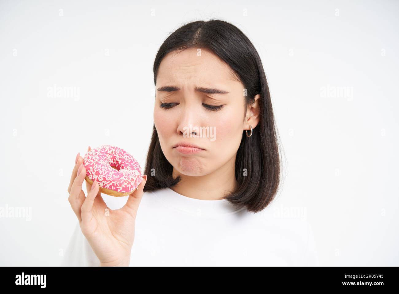 Crying asian woman showing tasty douhnuts and sobbing, being on healthy ...