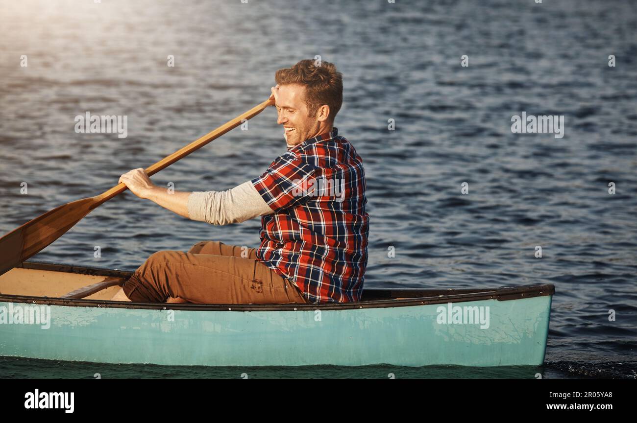 Happiest on the lake. a young man rowing a boat out on the lake Stock ...