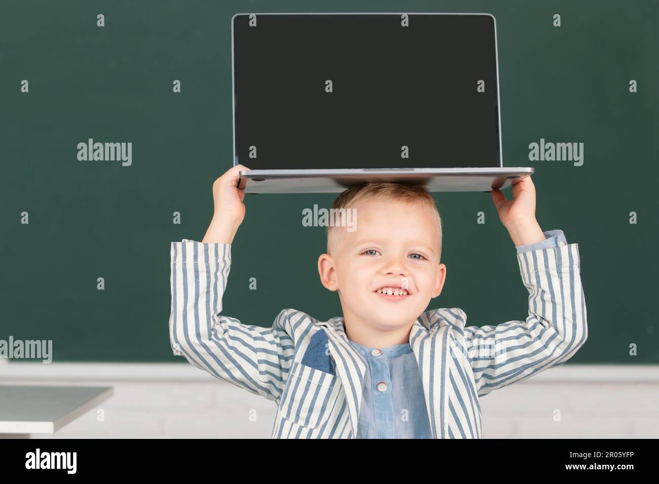 Elementary school kid holding laptop on head in computer class Stock ...