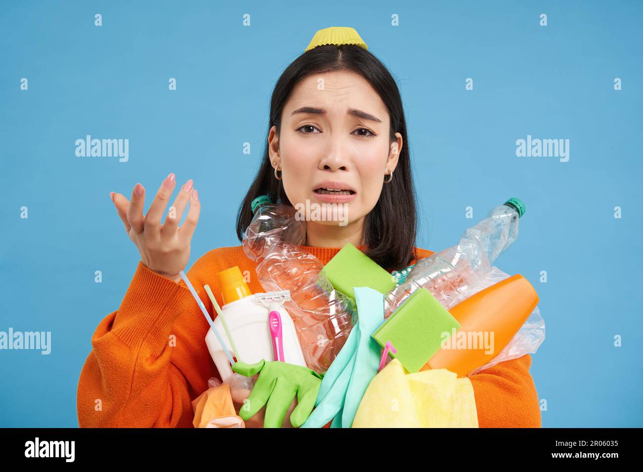 Frustrated asian woman crying, holding loads of empty plastic bottles ...
