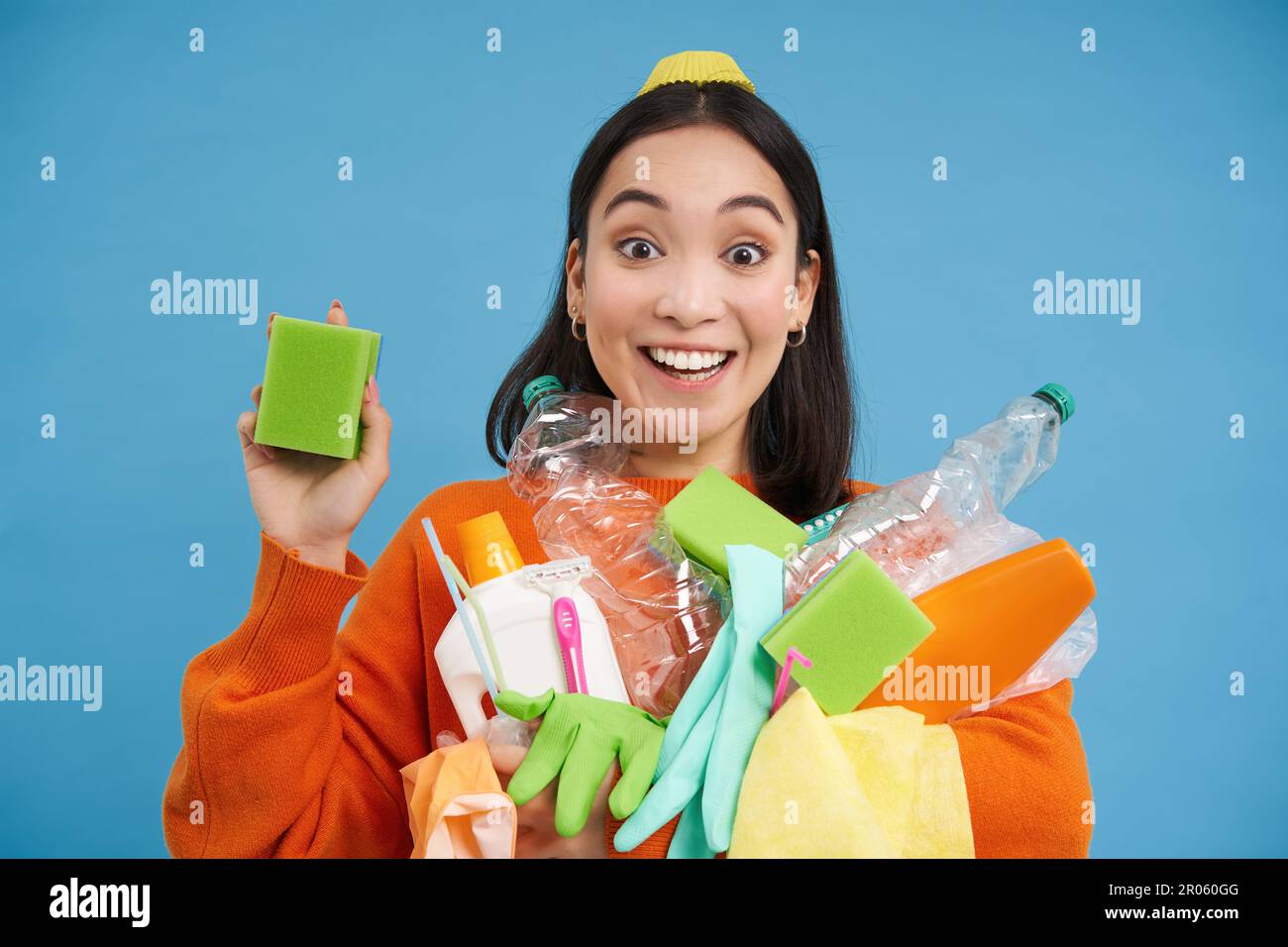 Enthusiastic asian girl showing cleaning sponge, holding empty plastic ...