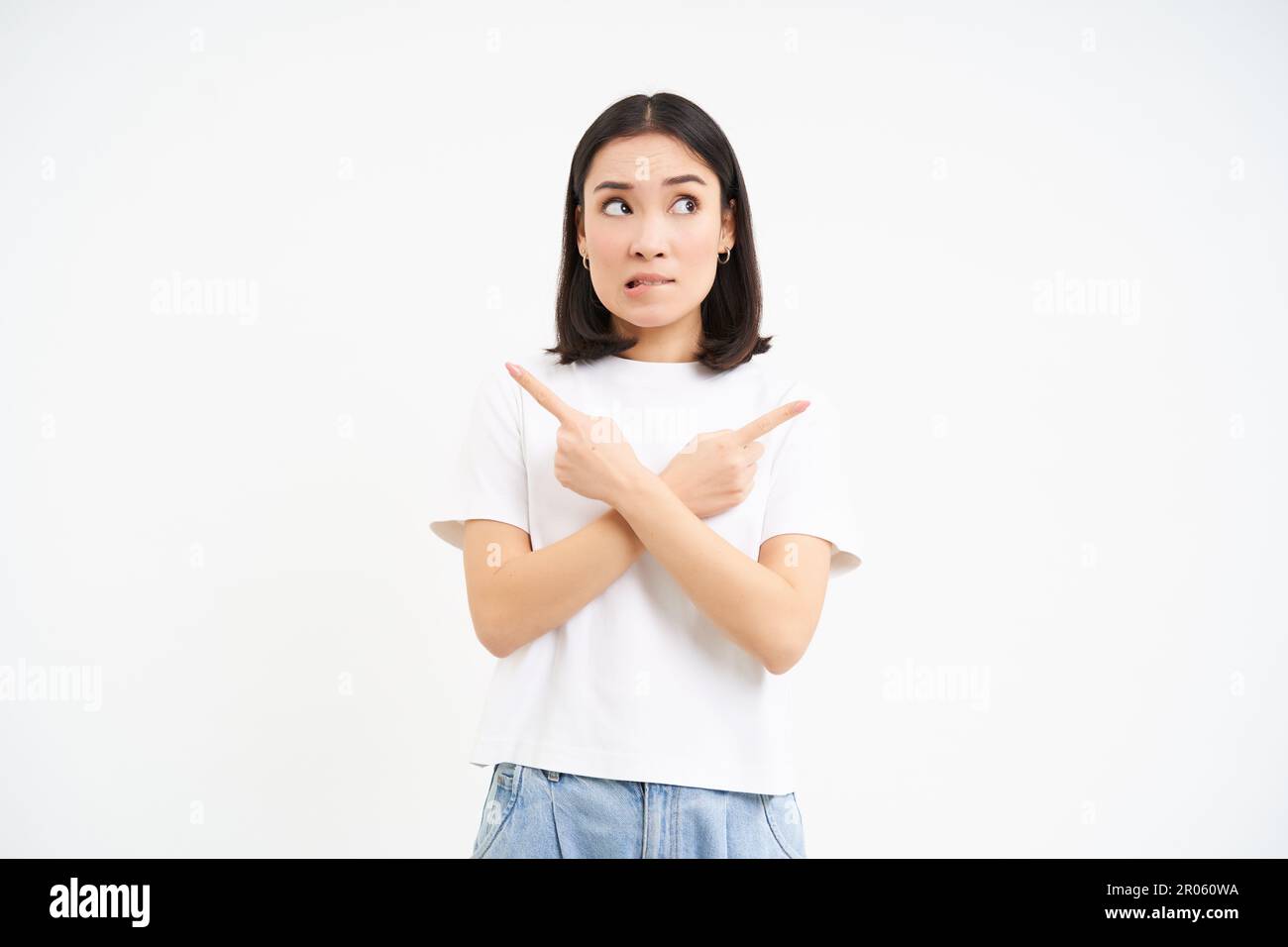 Thinking asian girl makes her decision, points sideways, two ways ...