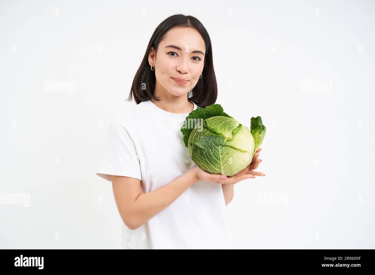 Lovely smiling woman, holding cabbage, posing with lettuce against ...