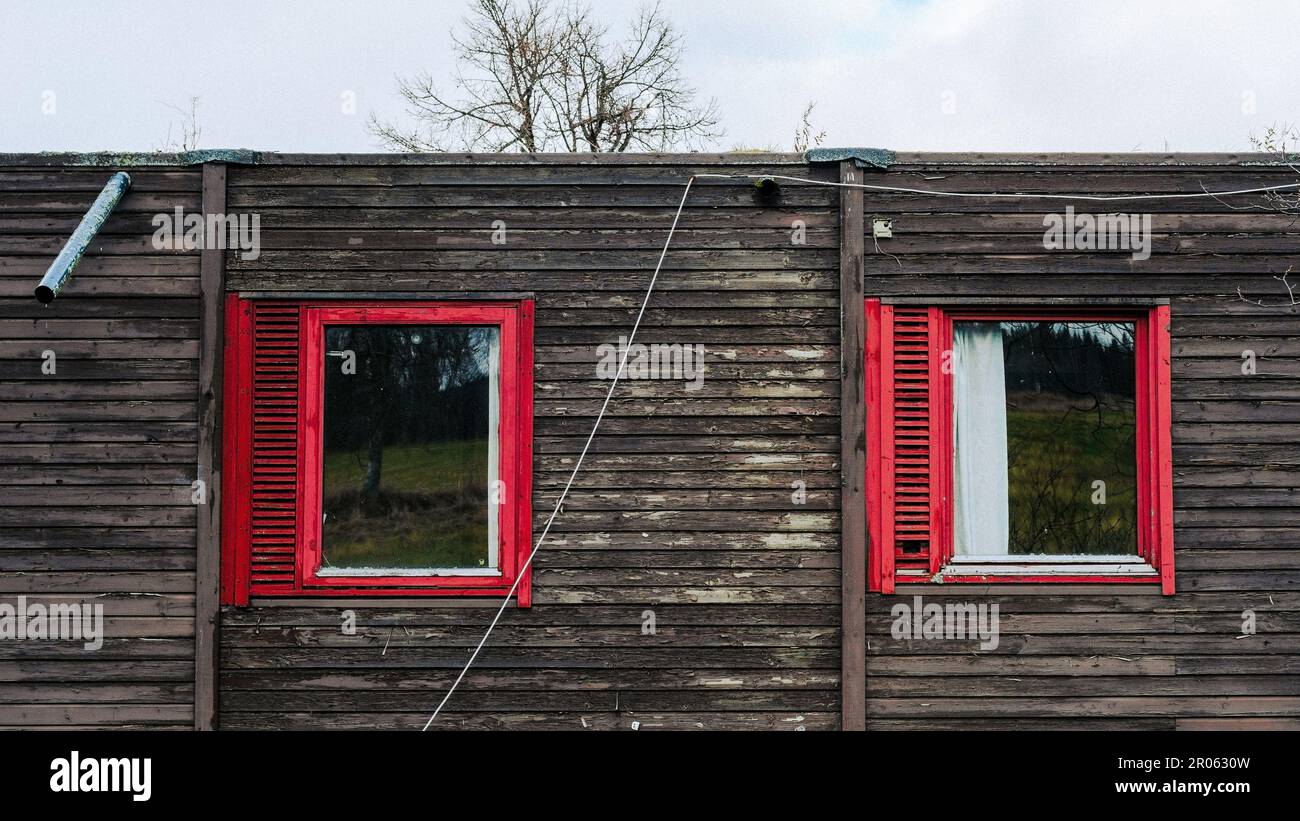 A rustic wooden building with two windows facing outward Stock Photo ...