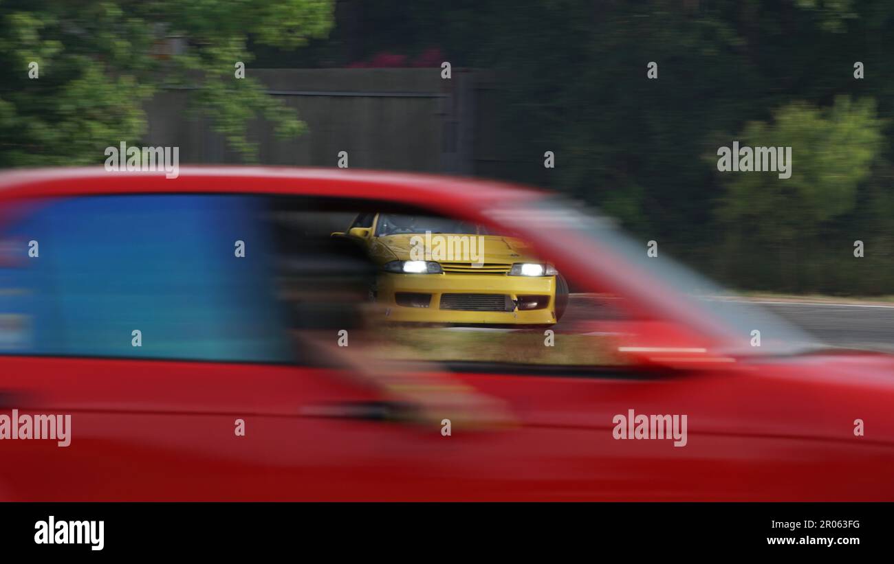 Yellow r32 sedan framed in the window of a red bmw e30 mid drift Stock ...