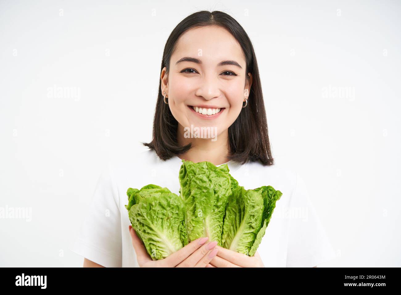 Vegetarian nutrition. Smiling happy young woman looks at her self grown ...