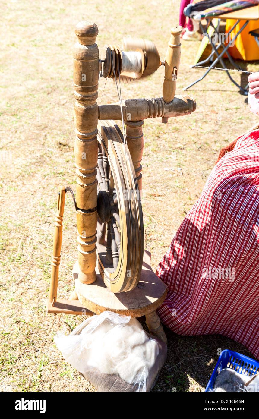 Woman in russian clothes demonstrating wool spinning on an old wooden ...
