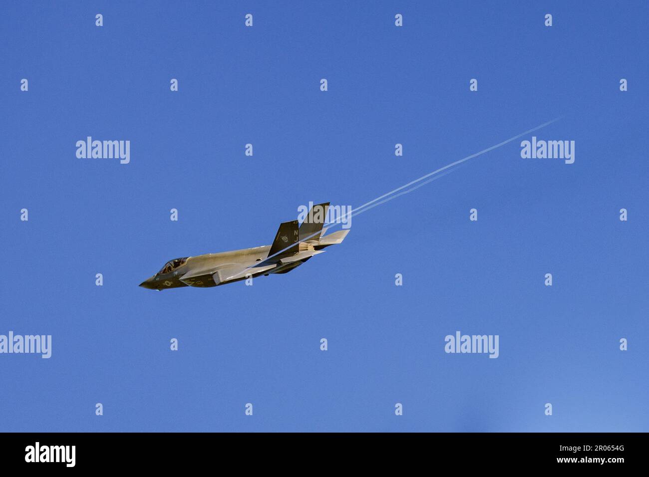 A sleek F-22 fighter jet soaring through a brilliant blue sky At ...