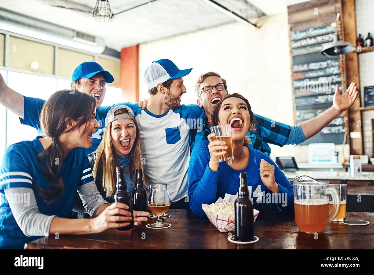 Awesome win, guys. a group of friends having beers while watching a ...