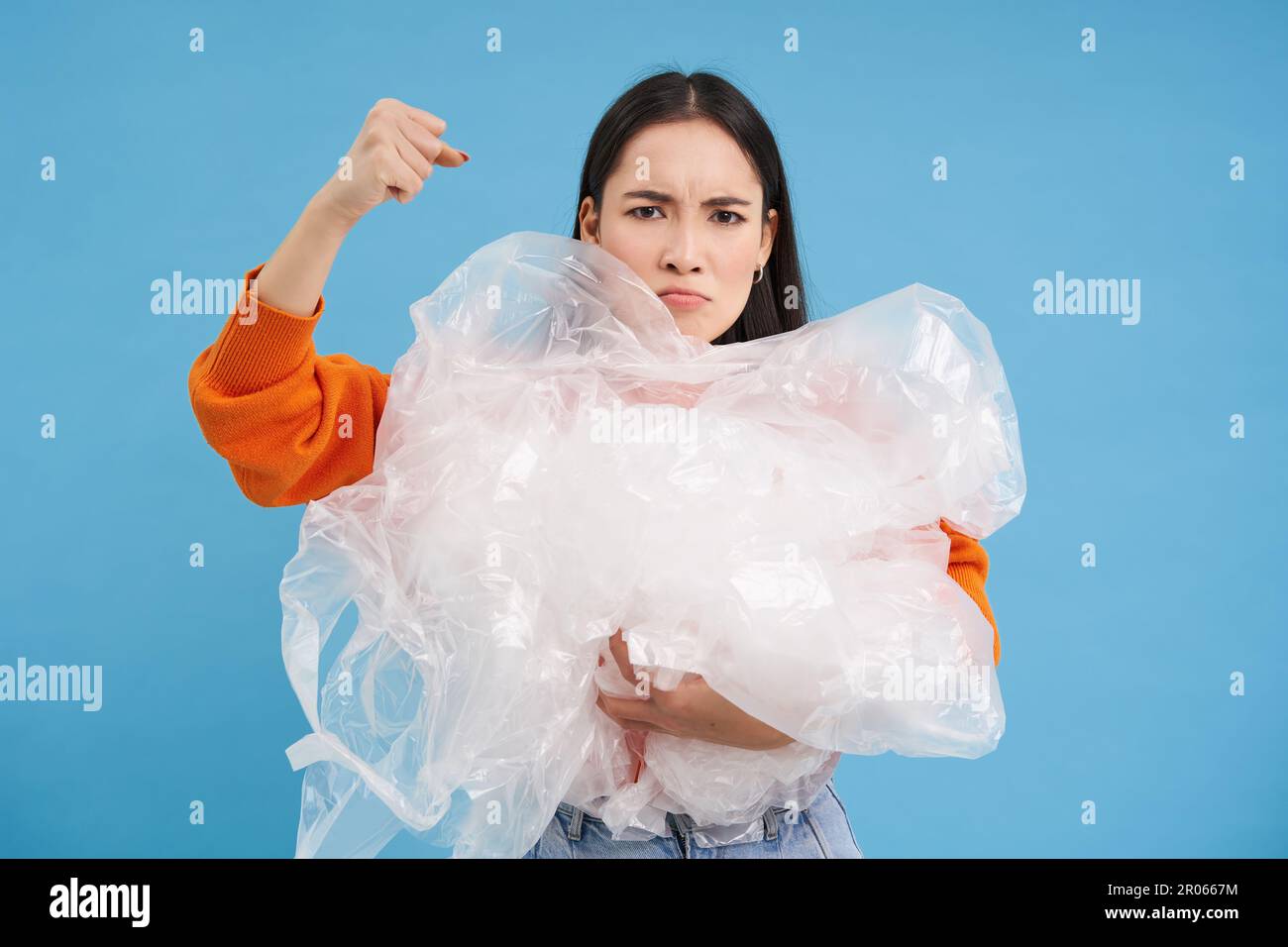 Angry eco-activist holding plastic waste, raising fist and fighting for ...