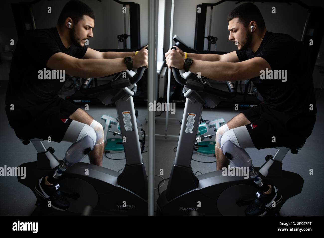 A soldier with a prosthetic leg trains on an exercise bike at a ...