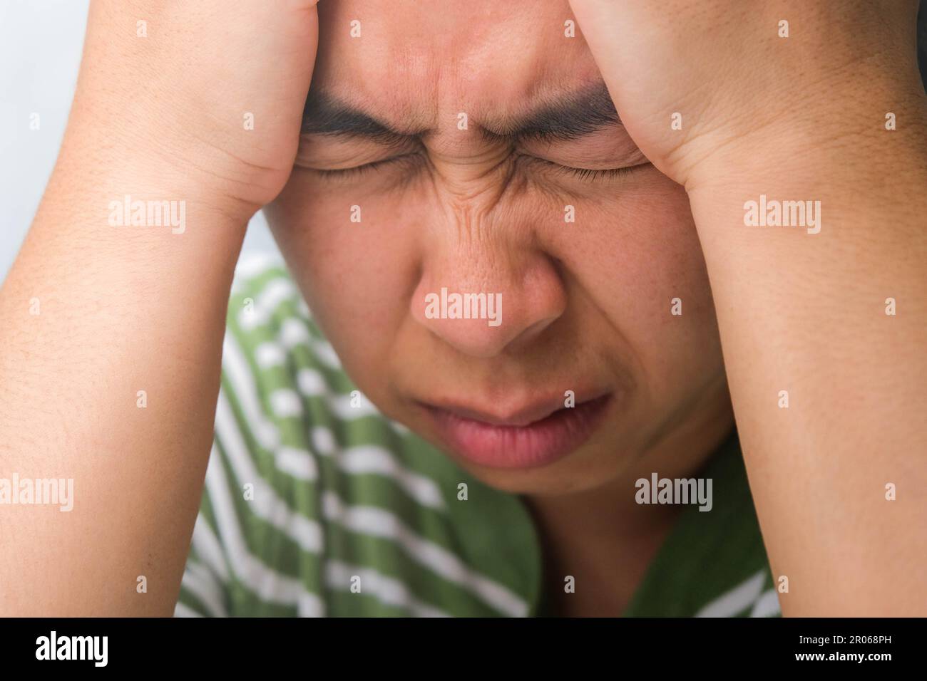 Young woman having headache against white curtain background in room ...