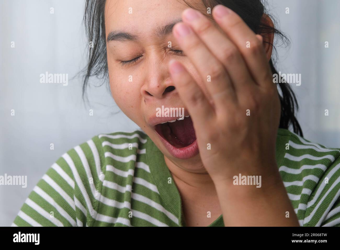 Tired woman yawning covering her mouth with her hands wanting to rest ...