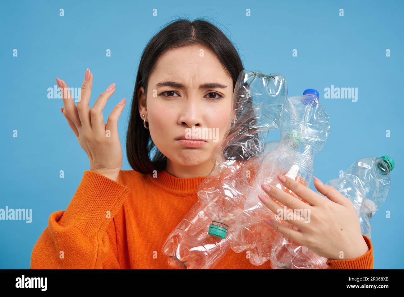 Woman with angry face, holding bottles, recycling plastic waste ...