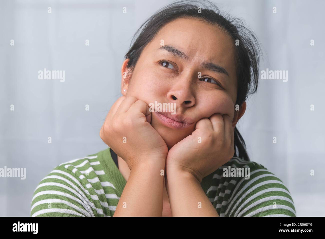 Bored woman sitting at desk at home. Asian woman who is bored, tired ...