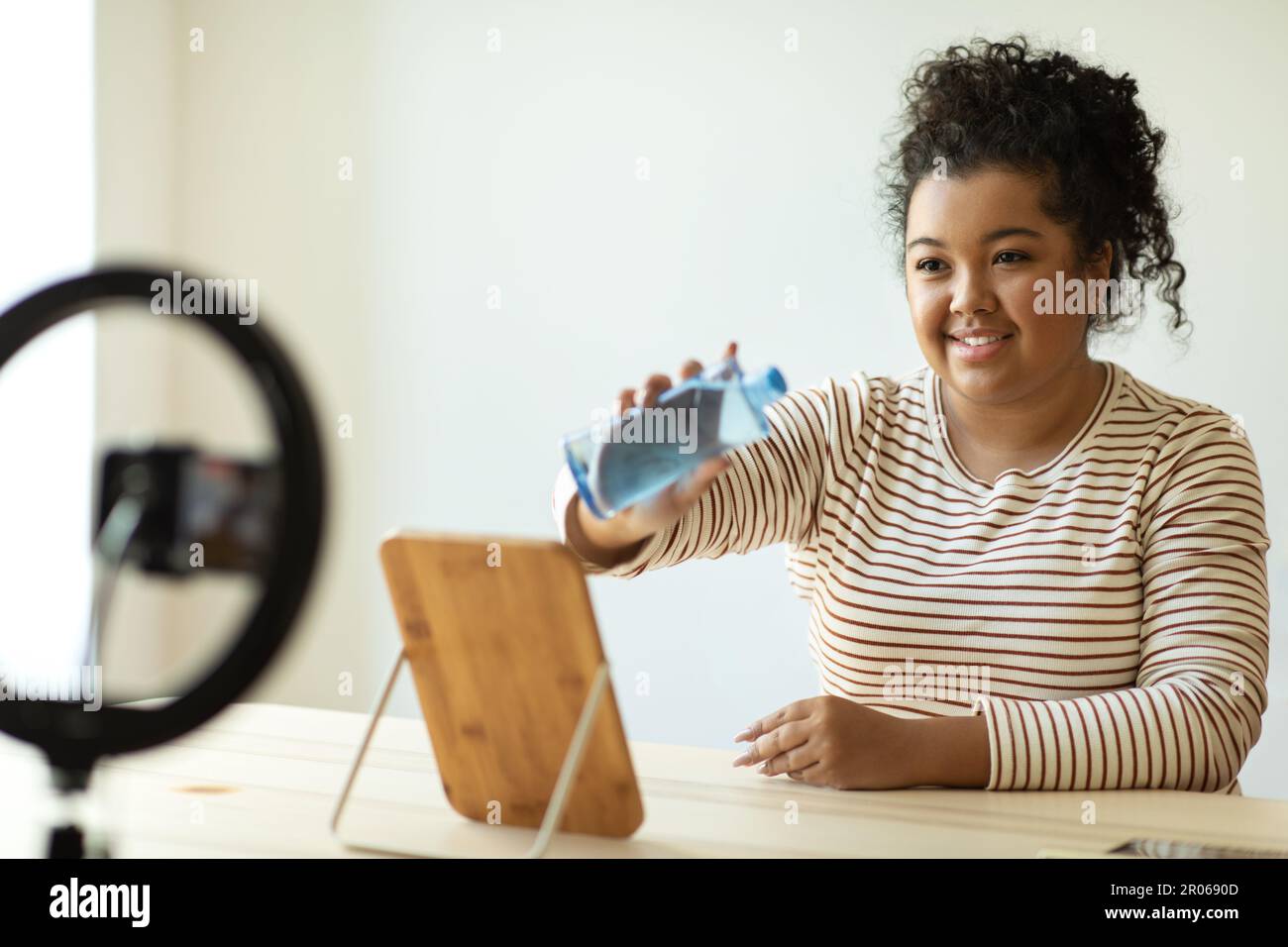 Cheerful young woman influencer recommending micellar water Stock Photo ...