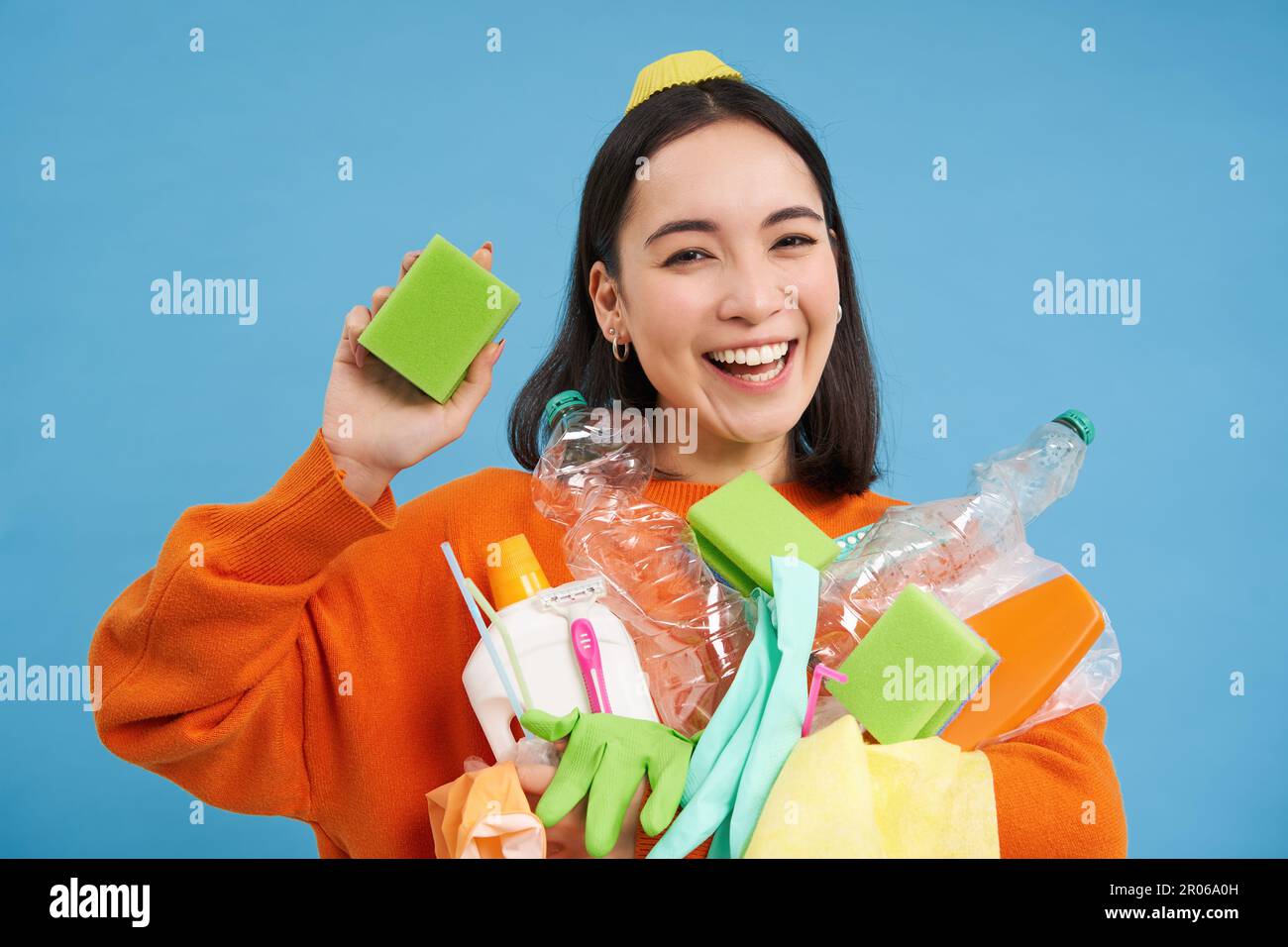 Portrait of enthusiastic smiling woman showing cleaning sponge, empty ...