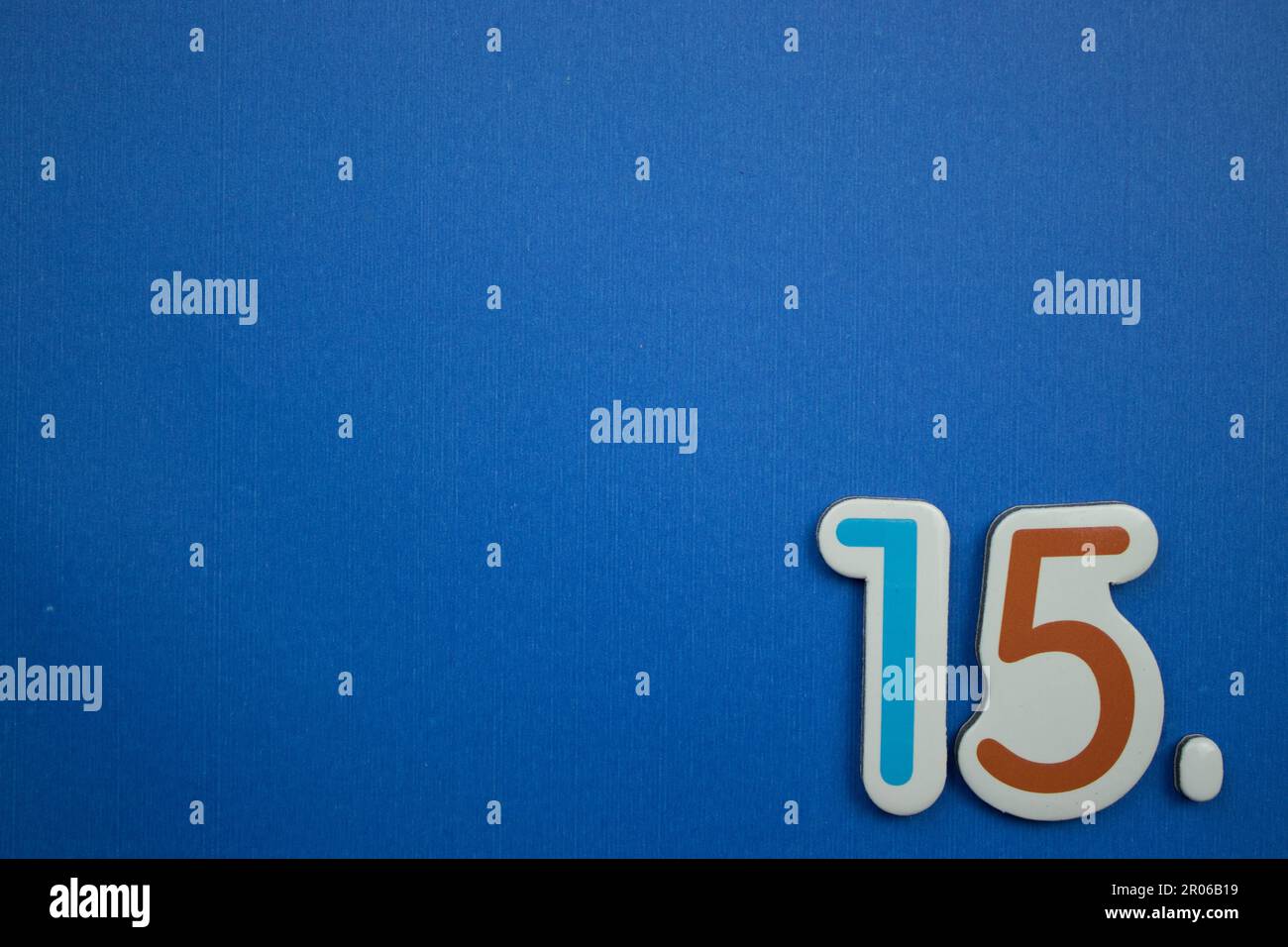 The number 15, placed on the edge of a blue background, photographed ...