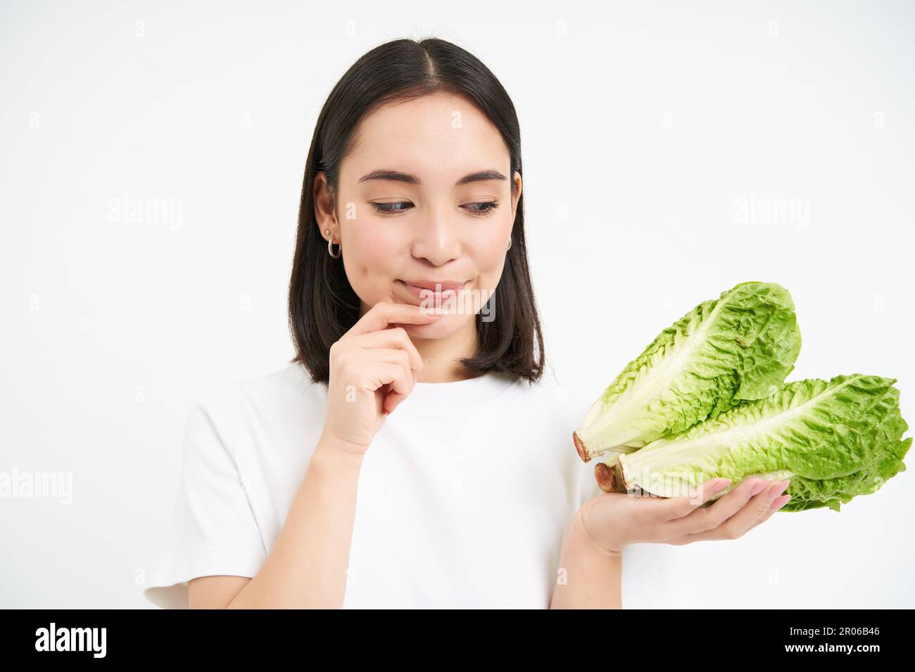 Girl with pensive face, shows cabbage, fresh raw food for people on ...
