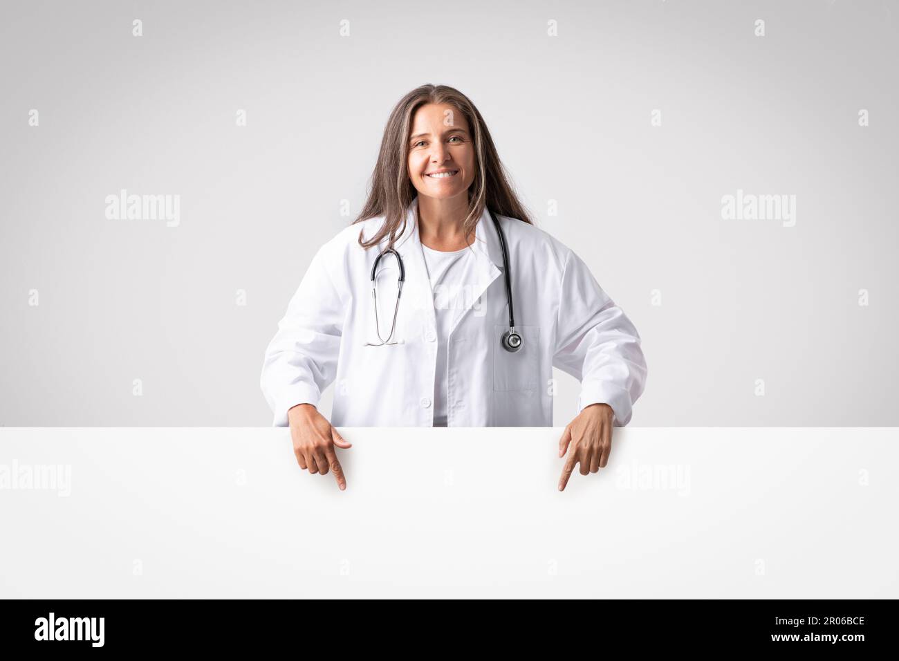 Great medical offer. Happy senior doctor woman pointing down at blank ...