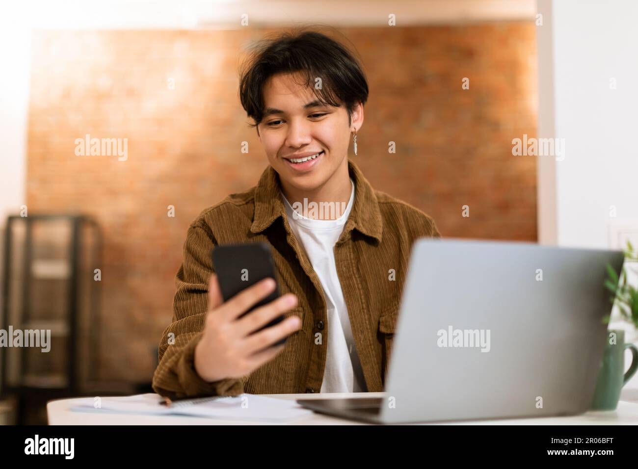 Korean Teen Boy Using Phone Learning Sitting At Laptop Indoors Stock ...
