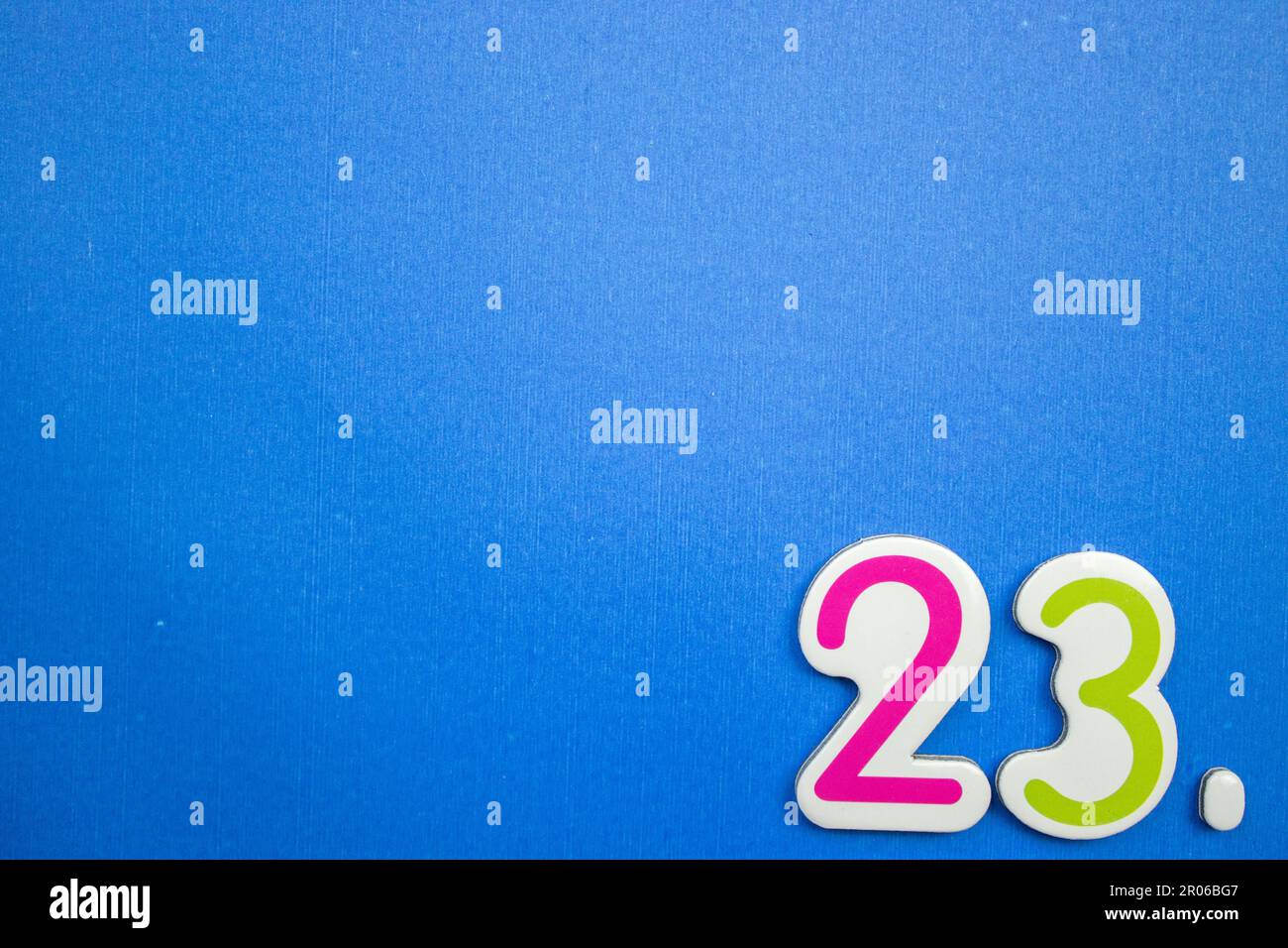 The number 23, placed on the edge of the blue background, photographed from above, colored red ...